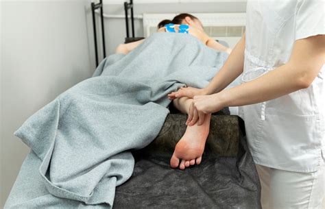 재활 전문가 물리 치료사가 뇌성 마비 척추 측만증 환자에게 발 마사지를합니다 건강 전문가 재활 평면 14 15 살에 대한 스톡