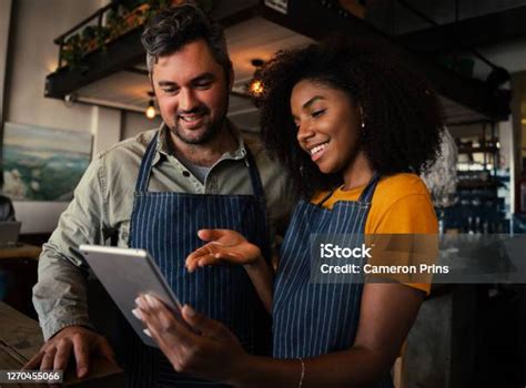 커피숍에 서 있는 태블릿을 보면서 계획을 논의하는 미소 짓는 남성과 여성 동료들 레스토랑에 대한 스톡 사진 및 기타 이미지