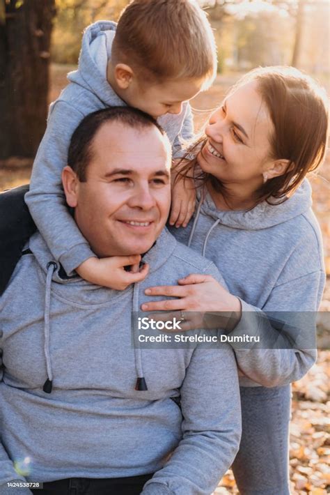 아버지의 어깨에 앉아있는 백인 어린 소년은 가을 공원에서 가족과 함께 산책을하고 있습니다 가을 공원의 야외 사진 일몰 광선 3