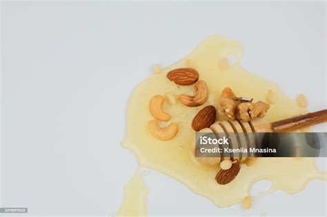 견과류 혼합물의 중앙을 클로즈업하면 액체 노란색 꿀 웅덩이에 놓여 있고 중앙에는 흰색 배경에 나무 숟가락이 클로즈업되어 있습니다 건강한 스낵 천연 디저트 달콤함의 컨셉 0