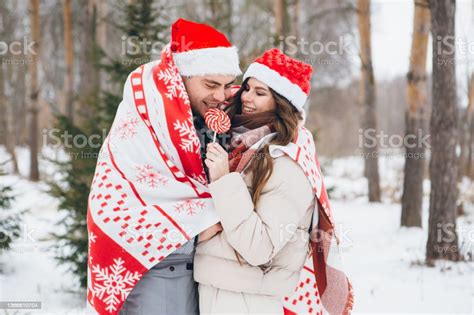 산타 모자를 쓰고 겨울 철엽 숲에서 격자 무늬 포옹과 키스에 싸여 있는 커플 커플에 대한 스톡 사진 및 기타 이미지 커플