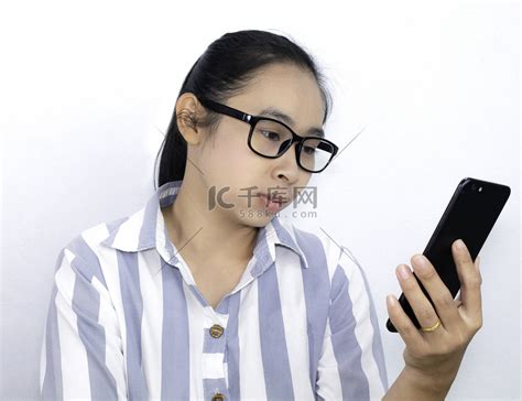 自信的商业亚洲年轻女性在白色背景下使用智能手机严肃的脸高清摄影大图 千库网
