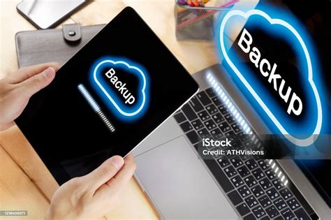 매력적인 아시아 남자는 클라우드 백업 서버에 백업 자신의 데이터를 동기화하기 위해 노트북과 태블릿을 사용하여 집에서 일하는 동안