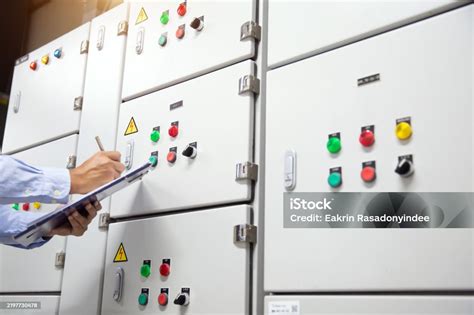 전기 엔지니어가 에어컨 또는로드 센터 캐비닛 또는 소비자 장치의 공기 처리 장치 스타터 제어 패널을 점검하고 주 배전실에서 전류 전압을 확인합니다 건설 산업에 대한 스톡