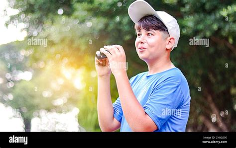 Asian Boy Using A Binocular To Do Bird Watching In The Local Park To