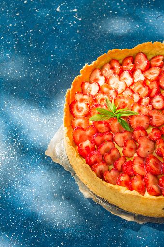 커스터드 바닐라 크림으로 채워진 신선한 홈메이드 딸기 쇼트크러스트 타르트 파이 트렌디 한 팬텀 블루 코스모스 배경에 슬라이스 베리와 민트 잎 복사 공간이 무료입니다 맨 위