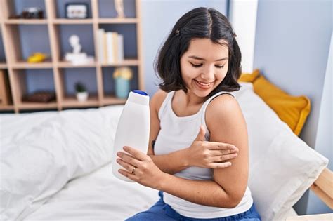 침실에서 침대에 앉아있는 팔에 로션을 바르는 젊은 여성 라틴 아메리카 히스패닉 민족에 대한 스톡 사진 및 기타 이미지 라틴 아메리카 히스패닉 민족 피부 관리 라틴