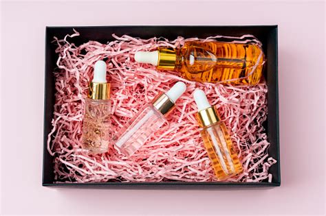 블랙 뷰티 기프트 박스와 화장품 세럼 잘게 썬 핑크 페이퍼 Aqainst 핑크 배경이 있는 병 선물 상자에 대한 스톡 사진 및 기타 이미지 Istock
