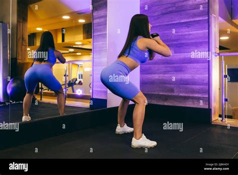 Young Beautiful Sports Woman In The Gym Doing Exercises Squats In