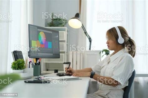 그래픽 태블릿과 스타일러스 펜을 사용하여 홈 오피스에서 새로운 프로젝트를 진행하는 젊은 창의적인 여성 편집 작품의 측면 보기