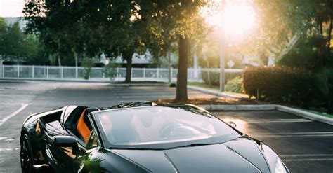 거리 검은 차 경치가 좋은 고성능 공기 역학의 교통 나무 낮 노려보다 다이나믹한 도시의 독특한 럭셔리 로드스터 매끄러운 반사 비싼 빛나는 표면