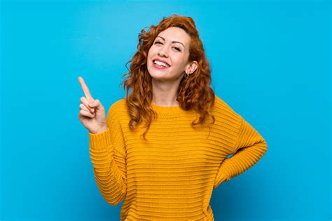 빨간 머리 여자 와 노란색 스웨터 표시 하 고 리프팅 A 손가락 에 기호 의 가장 좋은 노랑에 대한 스톡 사진 및 기타 이미지