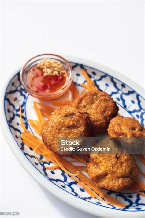 파란색 패턴의 도자기 접시에 담긴 태국 전통 돗문 플라 어묵 달콤한 칠리 디핑 소스와 잘게 썬 당근 레스토랑 브랜딩 및 음식 사진 촬영을 위한 정통 태국 애피타이저 0명에