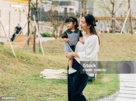 아시아의 어머니는 잘 관리된 공원의 고요한 환경 속에서 딸을 안고 있습니다 2명에 대한 스톡 사진 및 기타 이미지 2명