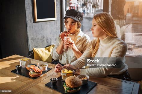 두 아름 다운 청소년 카페에서 테이블에 앉아서 왼쪽을 보세요 처음 마시는 칵테일 친구 외 두 번째 앉아입니다 그들은 Aat