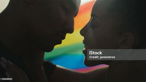 Lgbt 프라이드 축하 무지개 깃발 앞에서 낭만적인 포옹에 서 있는 유색인종 퀴어 Lgbt 프라이드의 달에 대한 스톡 사진 및 기타 이미지 Lgbt 프라이드의 달