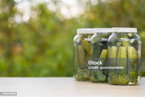정원의 테이블에 세 유리 항아리에 통조림 오이의 클로즈업 야외 수제 햇볕이 잘 드는 오이 절인 가정 생활에 대한 스톡 사진 및