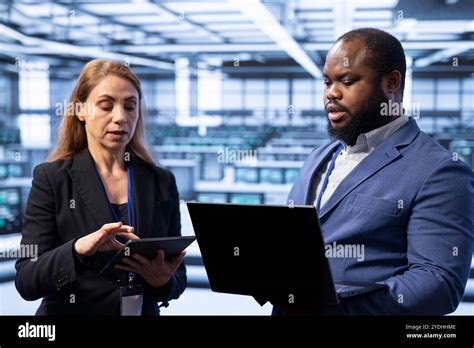 Team Of Technicians In Server Room Using Laptop To Implement And Maintain Security Measures