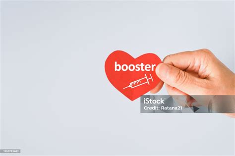 코로나 바이러스 인구 사회 또는 무리 면역 개념의 확산으로 인해 예방 접종 또는 접종 부스터 복용량부스터 용량부스터 단어와 주사기 아이콘빨간 심장 종이 모양을 들고 있는