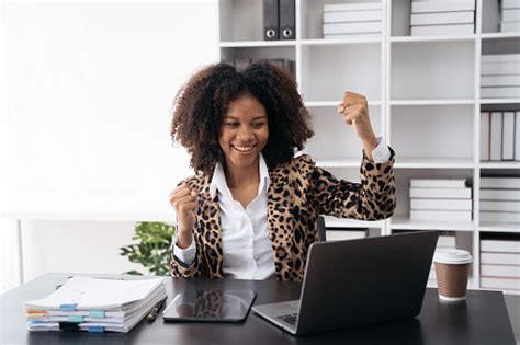 성공한 비즈니스 여성 흥분한 젊은 여성 팔짱을 끼고 긍정적인 감정을 보여주고 컴퓨터로 현대 사무실에서 일하는 것을 행복하게 여긴다 20 24세에 대한 스톡 사진 및 기타