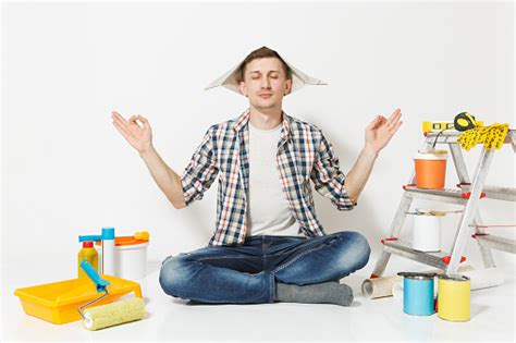 명상 요가 하 고 재건축 아파트 룸 흰색 배경에 고립에 대 한 악기와 함께 편안 하 게 바닥에 앉아 신문 모자에 행복 한 남자 벽지 붙이는 도구 수리 가정 개념입니다