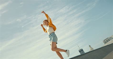 도시의 야외에서 여자와 함께 춤 자유 푸른 하늘 여름에는 신선한 공기를 마시며 즐거운 시간을 보냅니다 패션 에너지 햇살이 도시 마을에서 혼자 춤을 추는 매력적인 젊은 여성과