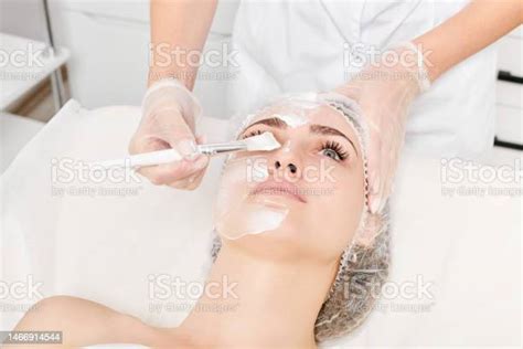 미용사는 회춘 얼굴 피부 미용실의 절차를 위해 여성 얼굴에 크림 마스크를 적용합니다 25 29세에 대한 스톡 사진 및 기타