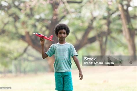 야외에서 장난감 비행기를 가지고 노는 아프리카계 미국인 소년의 초상화 공원에서 장난감 비행기를 가지고 즐거운 시간을 보내는 아이 행복한 흑인들 교육 및 견학 개념 비행기에