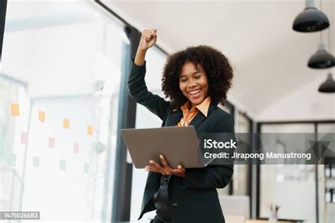 아름다운 젊은 십대 미국 아프리카 비즈니스 여성은 우승자에 손을 들고 컴퓨터 노트북을 들고 제스처입니다 성취 성공을 축하하는 성공을 기쁘게 생각합니다 기업가에 대한 스톡