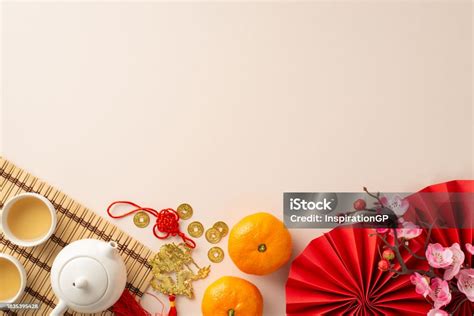 위에서 본 중국 설날의 아름다움 부채 풍수 보물 찻 주전자 세트 및 가족 관습에 대한 녹차 찬가 귤 벚꽃 파스텔 베이지 캔버스는 텍스트를 위한 완벽한 공간을 만듭니다 0명에