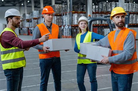 안전 헬멧과 작업복을 착용하고 상자를 들고 시선을 돌리는 성공적인 작업자 그룹 20 24세에 대한 스톡 사진 및 기타 이미지