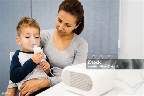 여자 어머니는 증기 증기 흡입기 분무기 마스크 흡입을 사용하여 그녀의 작은 아들 소년 아이를 집 이나 병원 의료 절차 약치료 치료 천식 폐렴 기관지염 기침 아픈 2 3 살에