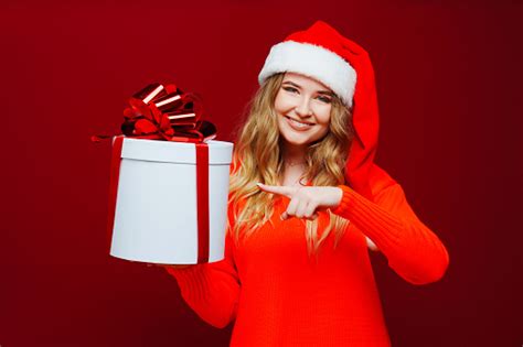 빨간 배경에 선물을 가진 산타클로스 모자를 쓴 아름다운 젊은 여성 12월에 대한 스톡 사진 및 기타 이미지 12월 20 24세 개념 Istock