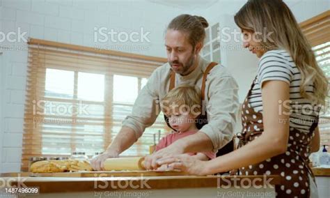 아버지와 어머니는 아기 아들이 집에 있는 부엌 카운터에서 반죽을 반죽하는 것을 가르친다 부모와 소년 아이는 실내 활동을 함께 즐기고 재미있게 요리합니다 3 명에 대한 스톡