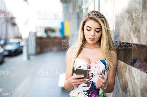 벽에 기대 고 있는 동안 그녀의 전화에 대 한 정보를 확인 하는 줄무늬 바지에 쾌활 한 여자 20 29세에 대한 스톡 사진 및 기타 이미지 Istock