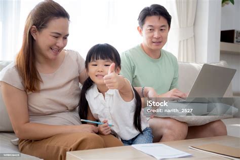 어머니가 숙제를 가르치는 행복한 가족 딸과 아버지가 집 거실 소파에서 노트북으로 일하는 모습 엄마가 아이와 함께 학업 라이프스타일 교육을 설명하는 행복한 가족 3 명에 대한