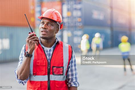 워키토키 무선 제어 적재 컨테이너 상자를 사용하는 감독 엔지니어 컨테이너 화물 현장에서 헬멧 작업을 통한 자신감 있는 엔지니어링 및 산업용 컨테이너 화물 운송 선박 점검