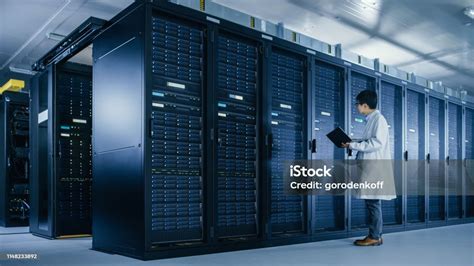 데이터 센터 서버 랙 옆에 흰색 코트를 착용 한 남성 It 전문가는 랩톱 컴퓨터를 사용 하 여 유지 관리 진단 도구를 실행 하 고 데이터베이스가 최적의 수준에서 작동 하도록