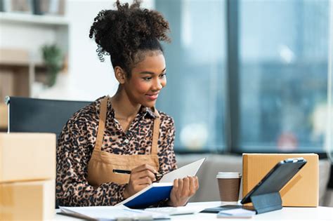 아프리카 갈색 머리를 가진 젊은 아프리카계 미국인 여성은 현대적인 사무실에서 일하며 전자 상거래 배송 및 마케팅 중소기업에 노트북 기술을 활용하여 소규모 비즈니스를