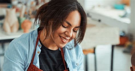 테이블에 앉아 사포로 도자기를 닦는 동안 미소 짓는 아름다운 젊은 여성 도예가 사진 Unsplash의 도기 이미지