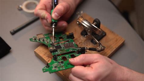 Top View Of Electronic Technician Using Soldering Iron To Repair Circuit Board Working On