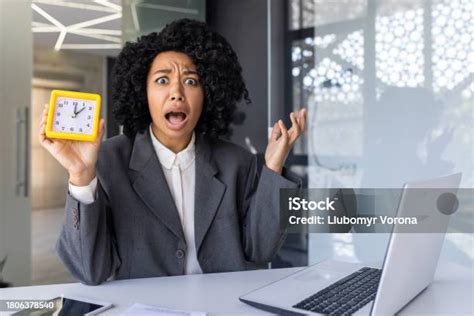 늦게까지 일하는 과로한 여성 카메라를 보고 있는 사업가 시계를 보여주며 화가 난 여성 사무실 한복판에서 노트북을 들고 피곤한 여성 직원 벽 시계에 대한 스톡 사진 및 기타