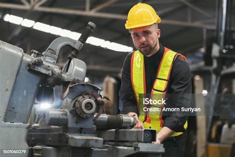 남성 엔지니어 노동자는 안전 유니폼 헬멧을 착용하고 산업 공장에서 선반 기계의 부품 품질을 검사하고 검사합니다 남성 기술자 작업자 작업장에서 기계의 유지 보수 부품 Cnc
