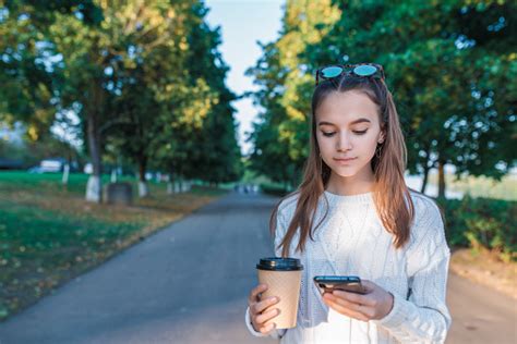도시 공원에서 여름에 십대 소녀 컵 커피 차 휴대 전화를 들고 소셜 네트워크에 Sms 온라인 응용 프로그램을 씁니다 텍스트 복사를 위한 여유 공간입니다 방과 후 개념 휴식