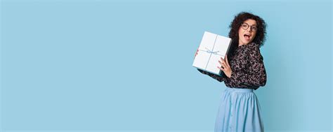 곱슬 머리 여자는 카메라에 파란색 여유 공간 근처에서 행복하게 포즈를 취하는 현재 상자를 보여주고 있다 상자에 대한 스톡 사진 및 기타 이미지 Istock