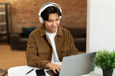 Premium Photo Cheerful Korean Guy Using Laptop Typing On Keyboard At Home
