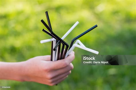 녹색 잔디 배경에 플라스틱 빨대의 꽃다발을 들고 손 플라스틱 오염 환경 폐기물 플라스틱 빨대에 아니오라고 말하십시오 우리의 녹색