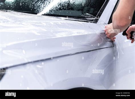 Paint Protection Film Installation On White Car Fender During