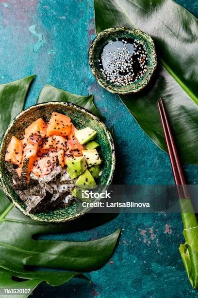 아보카도 쌀 세사모를 곁들인 하와이 연어 포크 포스를 열대 잎 그릇에 담아 서빙합니다 초밥 그릇 청록색 슬레이트 배경입니다 맨 위 보기 보울에 대한 스톡 사진 및 기타