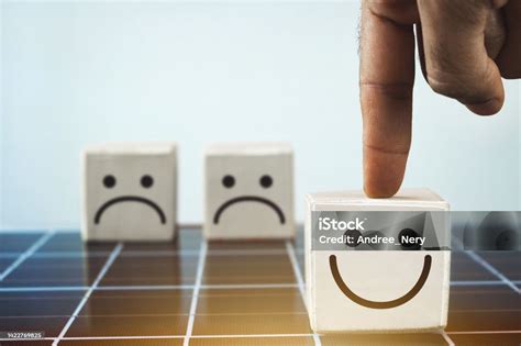 손은 밝은 쪽에는 미소 얼굴이 있고 슬픈 얼굴은 태양광 태양 전지 패널에 어두운 곳에 나무 큐브를 놓습니다 긍정적 인 사고 방식 청정 에너지 개념 감정에 대한 스톡 사진 및